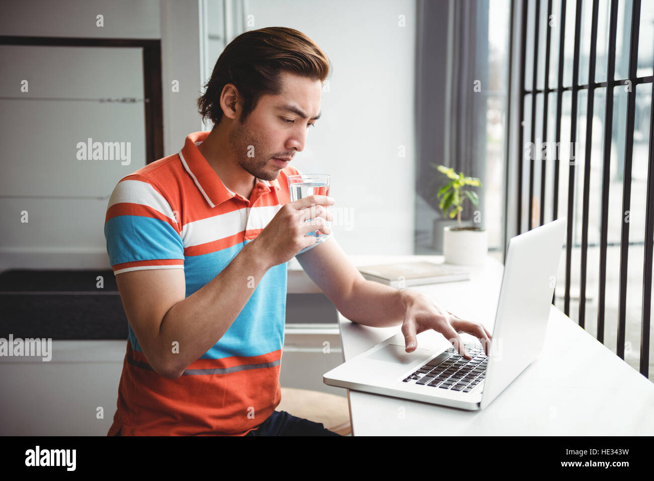 Man using laptop while drinking water in coffee shop Stock Photo - Alamy