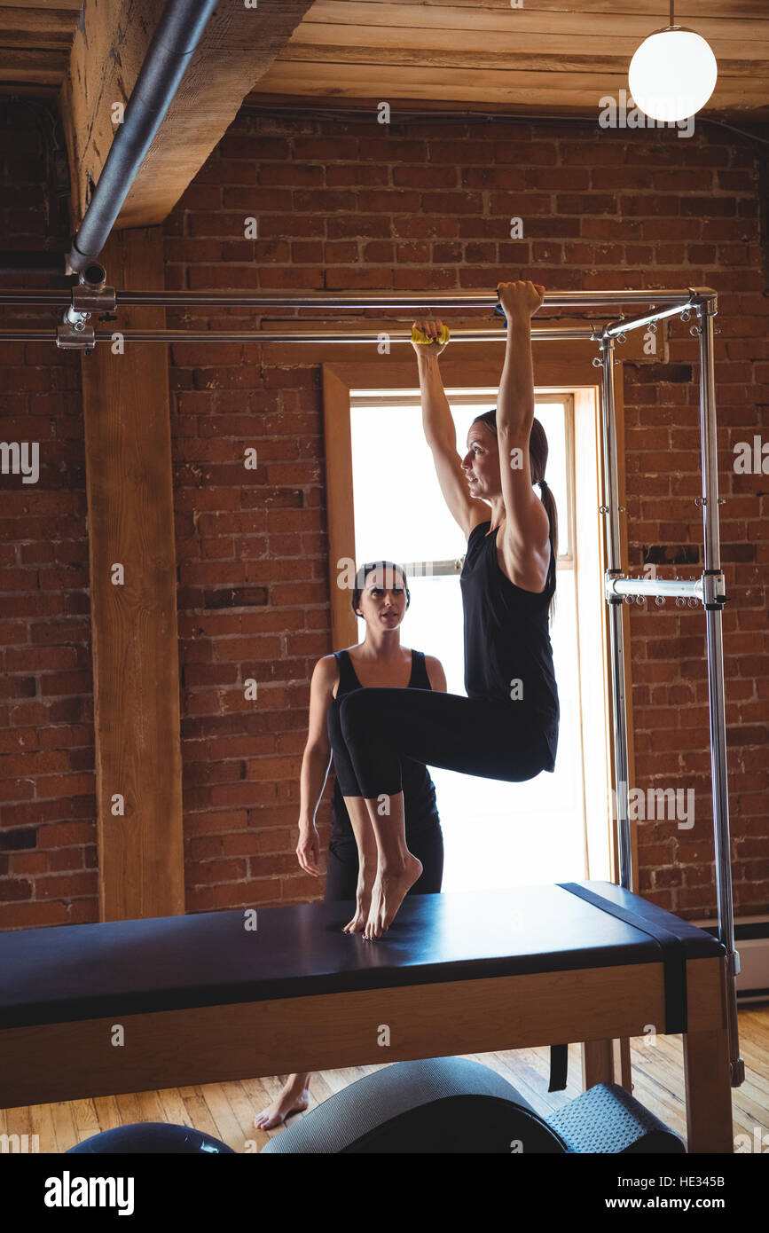 Trainer helping a woman while practicing pilates in fitness studio ...