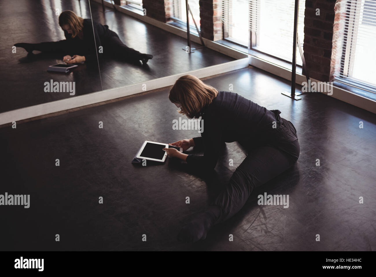 Dancer sitting on floor and using mobile phone in dance studio Stock ...