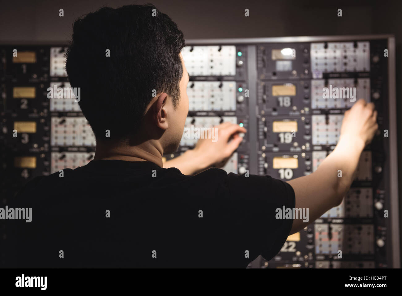 Rear view of audio engineer using track recorder in recording studio ...