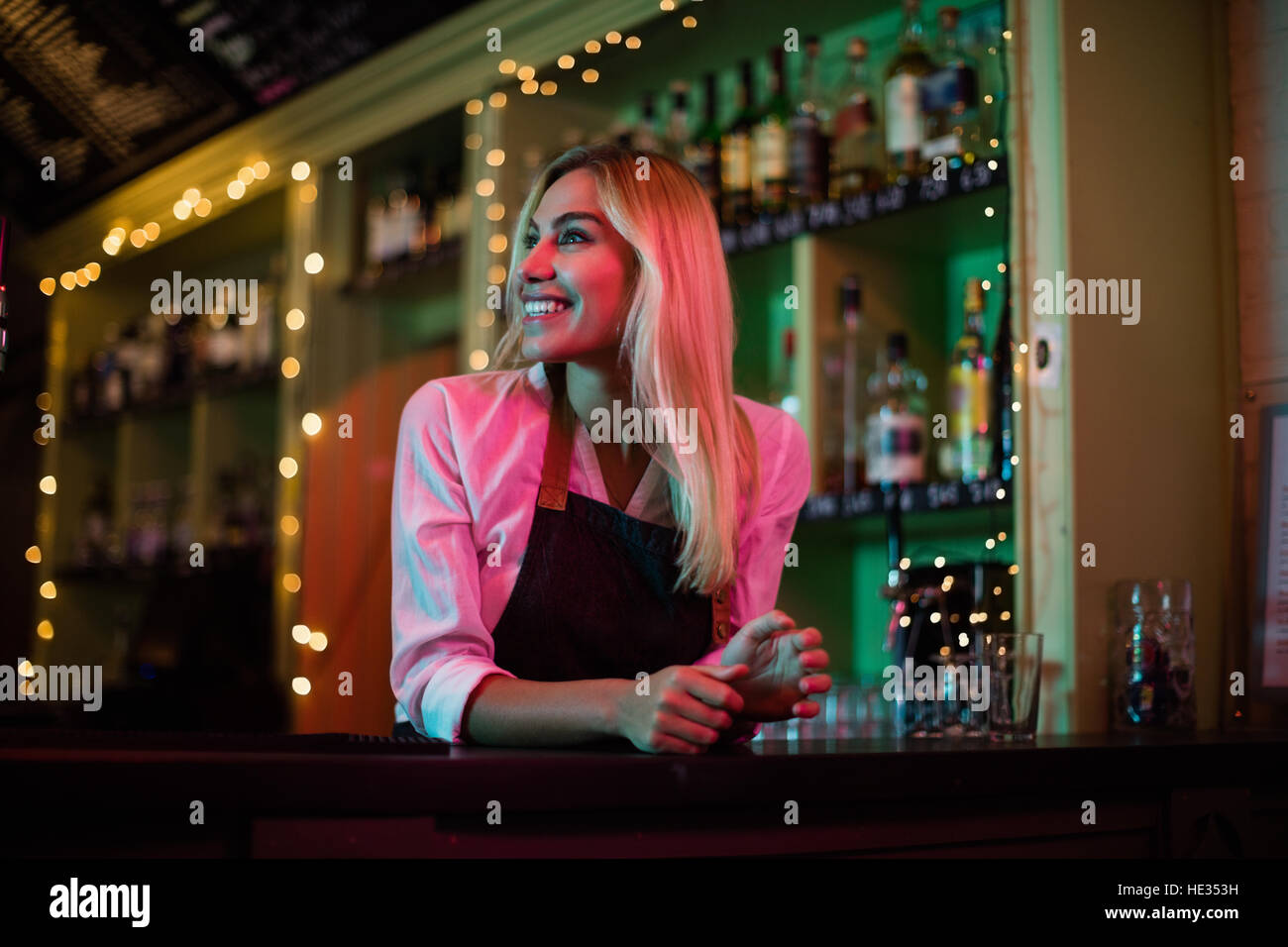 Beautiful smiling waitress leaning at bar counter Stock Photo - Alamy