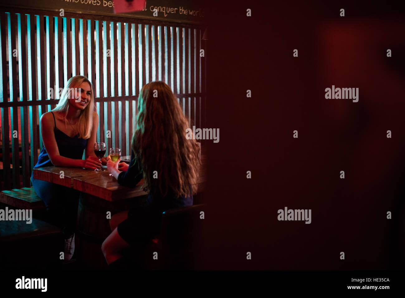 Two women interacting while having a glass of wine in bar Stock Photo ...