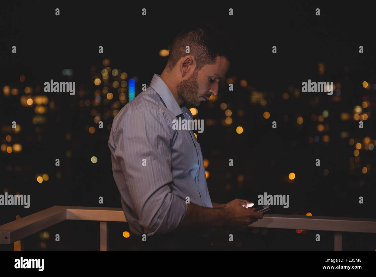 Man using his mobile phone in the balcony at night Stock Photo - Alamy