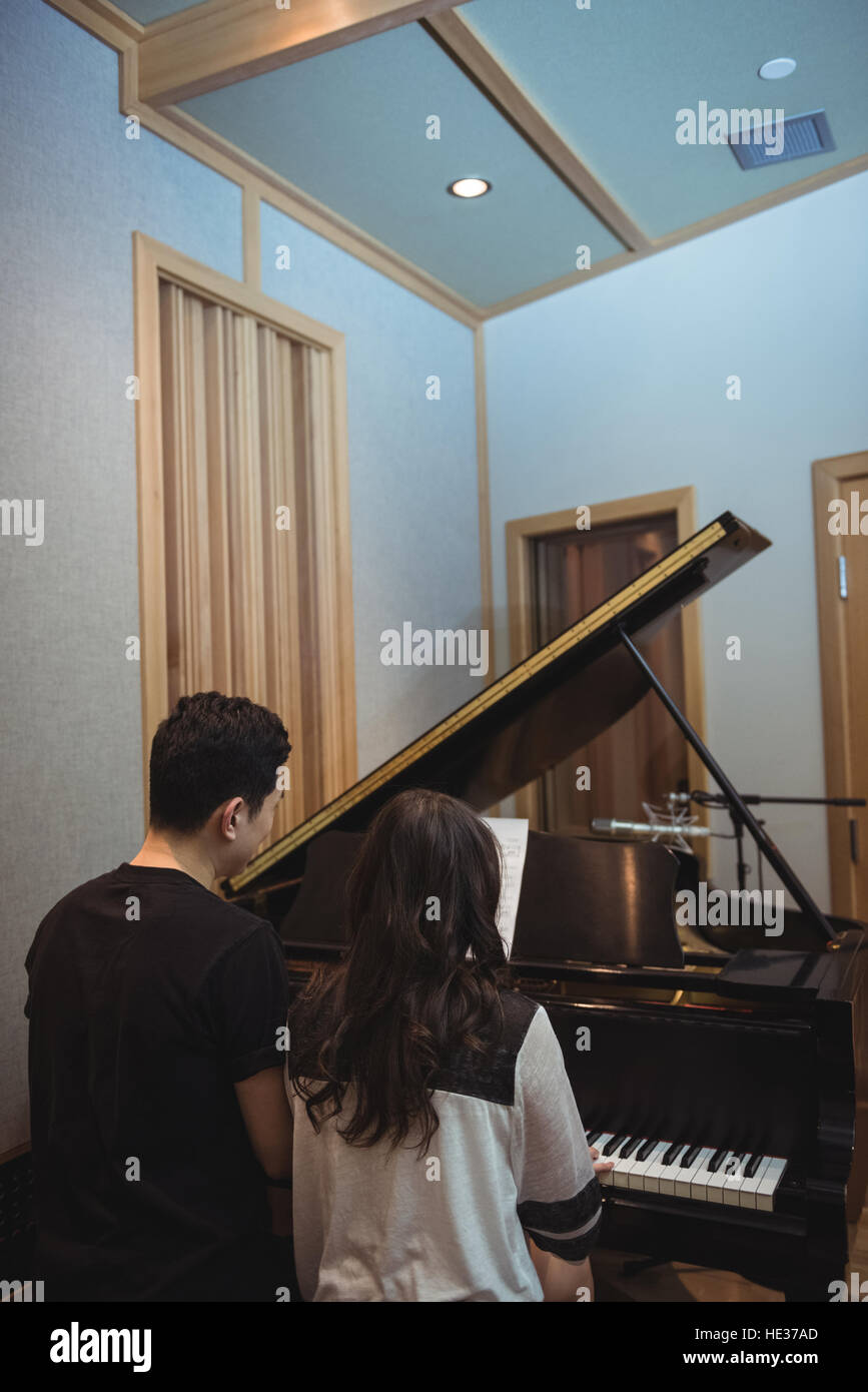 Rear view of couple playing a piano in recording studio Stock Photo - Alamy