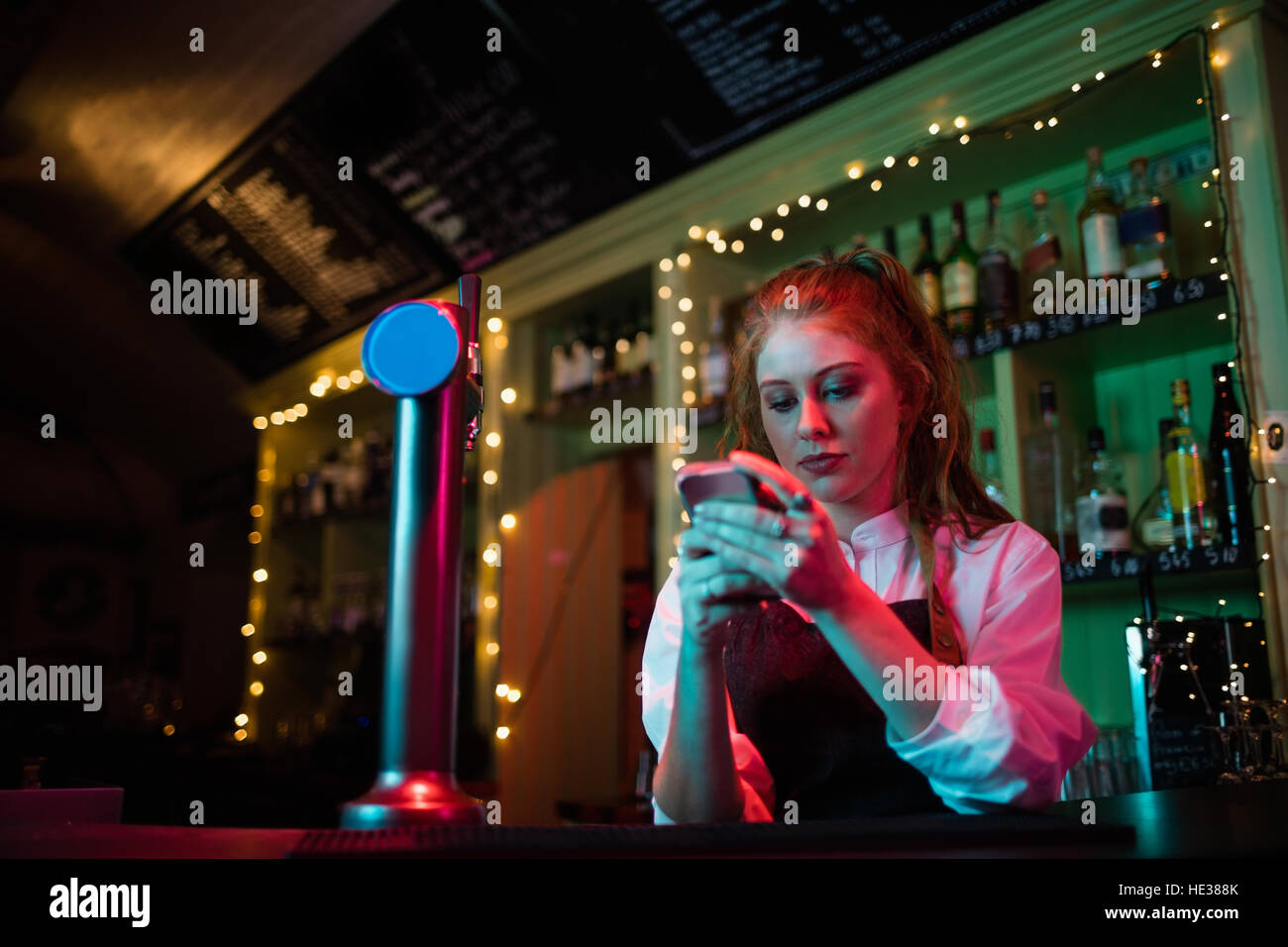 Waitress using her mobile phone at counter in bar Stock Photo - Alamy