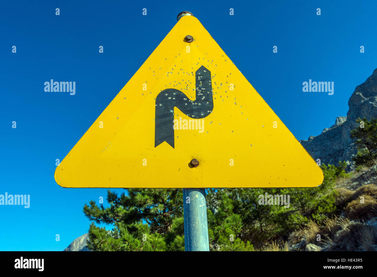 yellow bends warning sign with shotgun pellet marks bullet holes ...