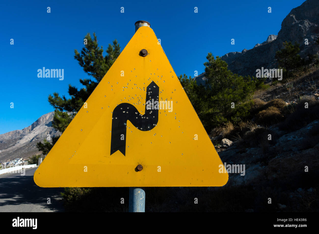yellow bends warning sign with shotgun pellet marks bullet holes ...