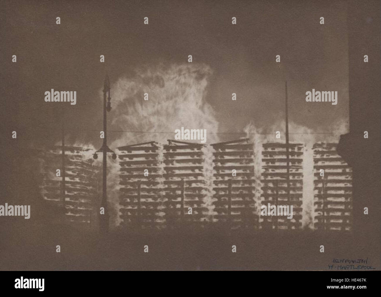 A dramatic historical image depicting stacks of timber ablaze in ...