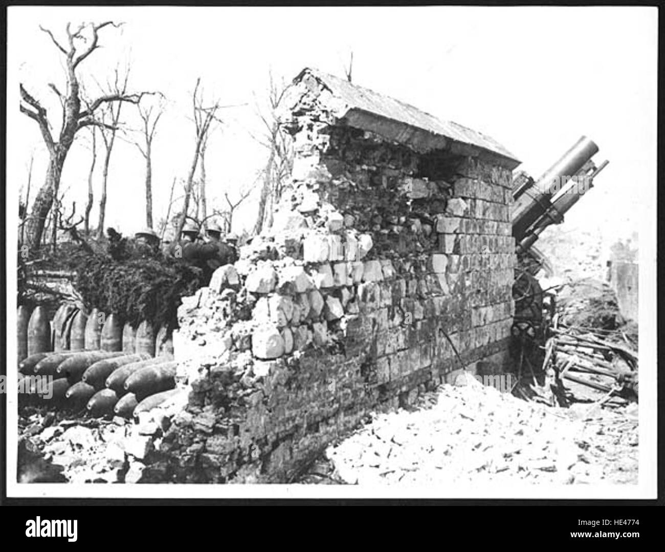 This historical photograph shows a howitzer firing next to a wall ...
