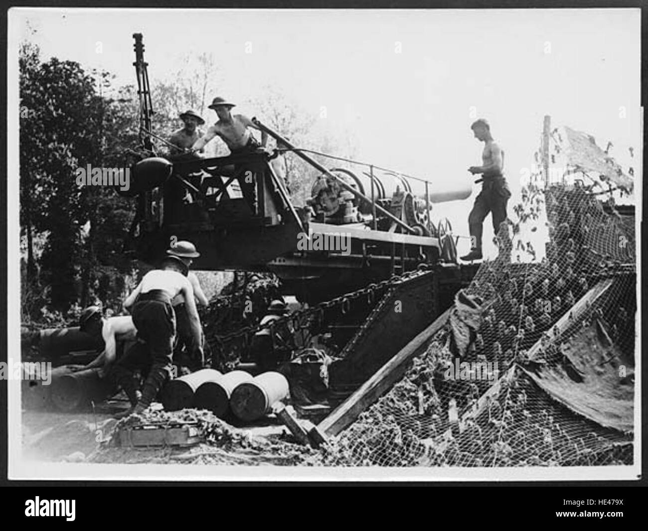 This historical image depicts gunners at work, stripped to the waist as ...