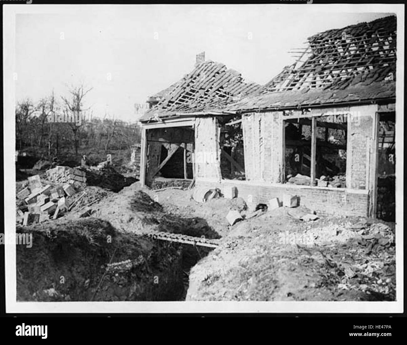 This historic image shows a trench running through a ruined village ...