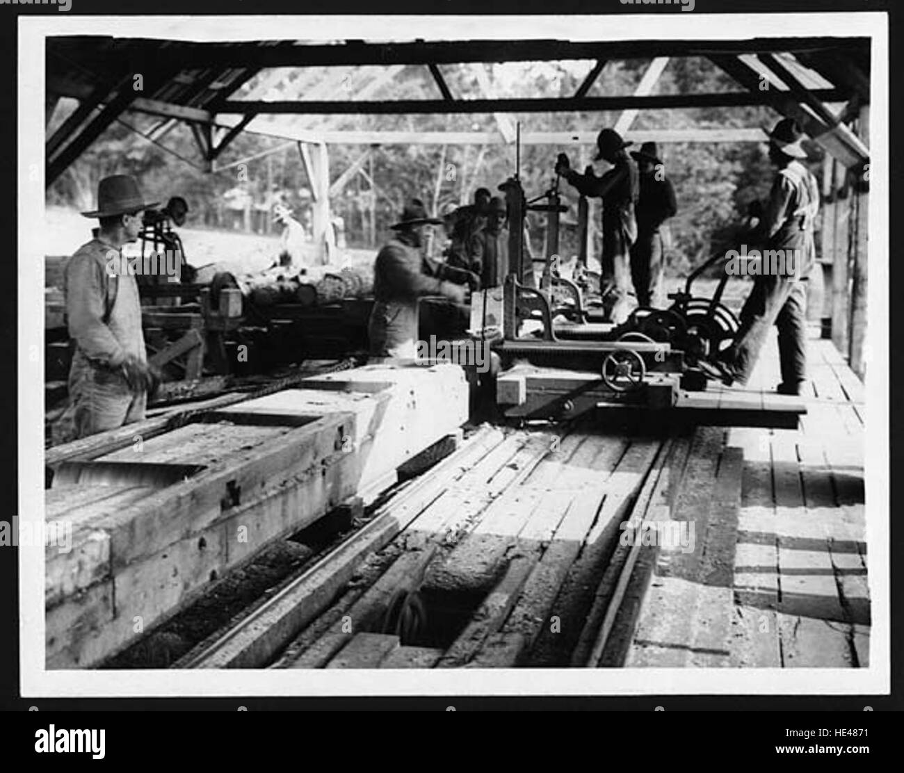 This historical image captures a scene inside a sawmill, showing ...
