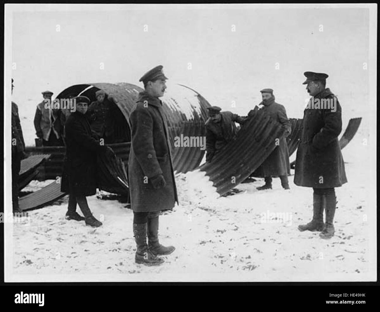 This historical image shows the construction of a Nissen hut in snowy ...
