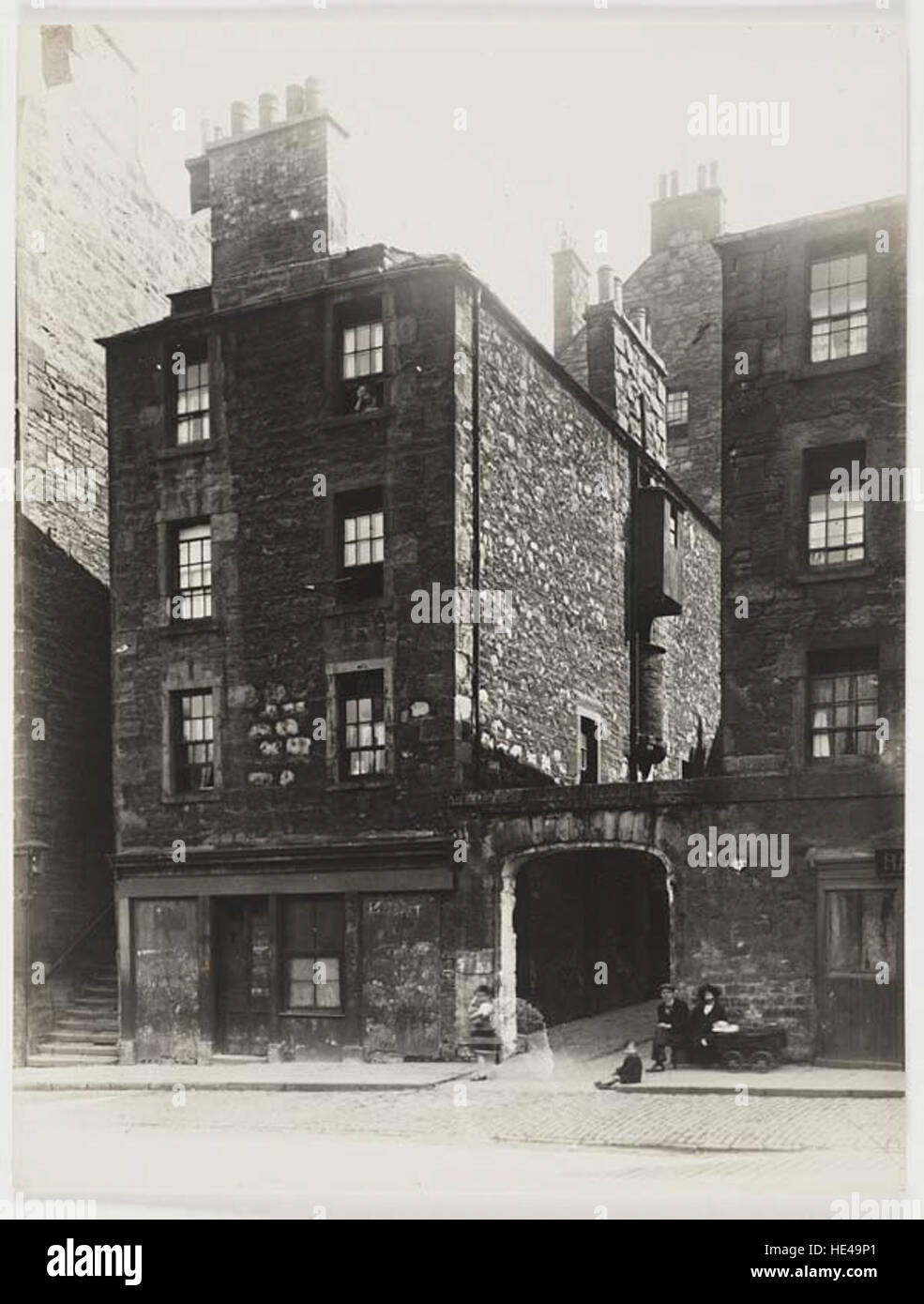 This historic image shows a detached three-story tenement building ...
