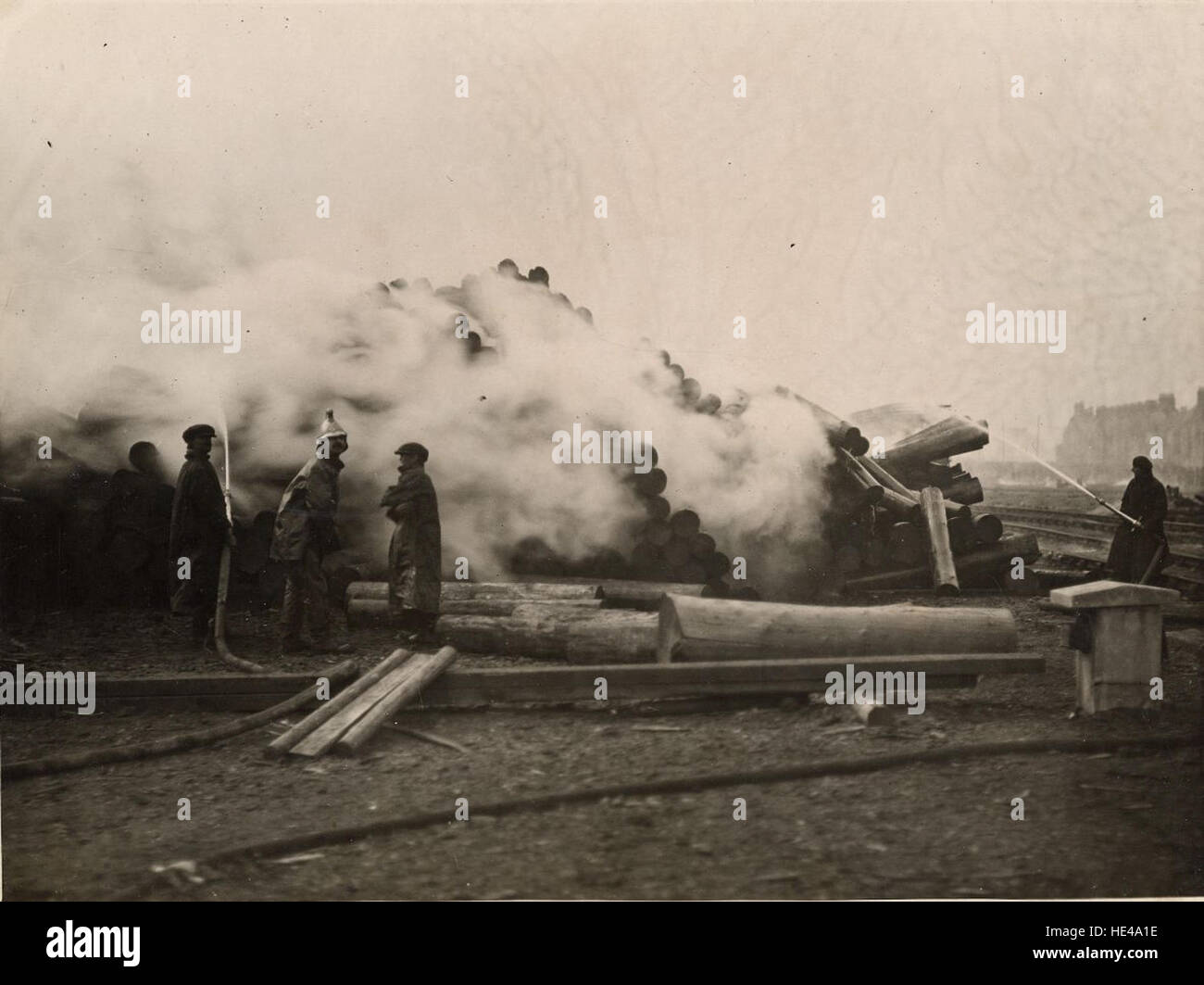This historical image shows a group of men battling a large fire ...