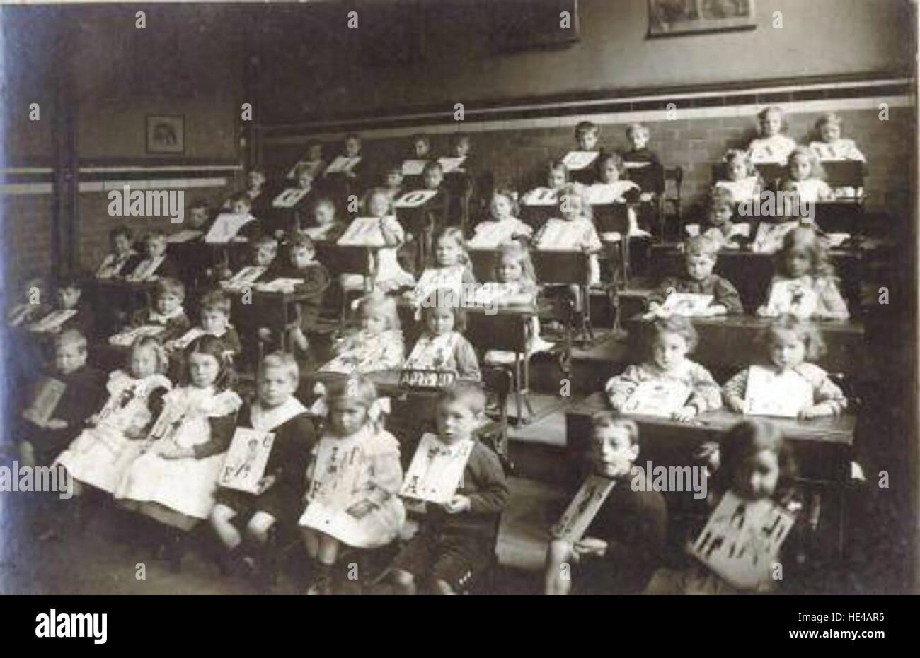 This historical photograph features a group of schoolchildren ...