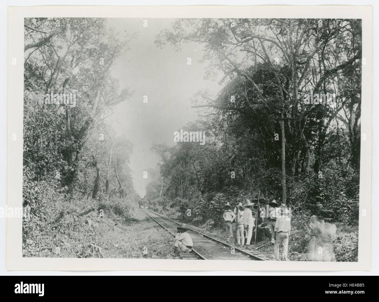A historical image showing men standing by railroad tracks ...