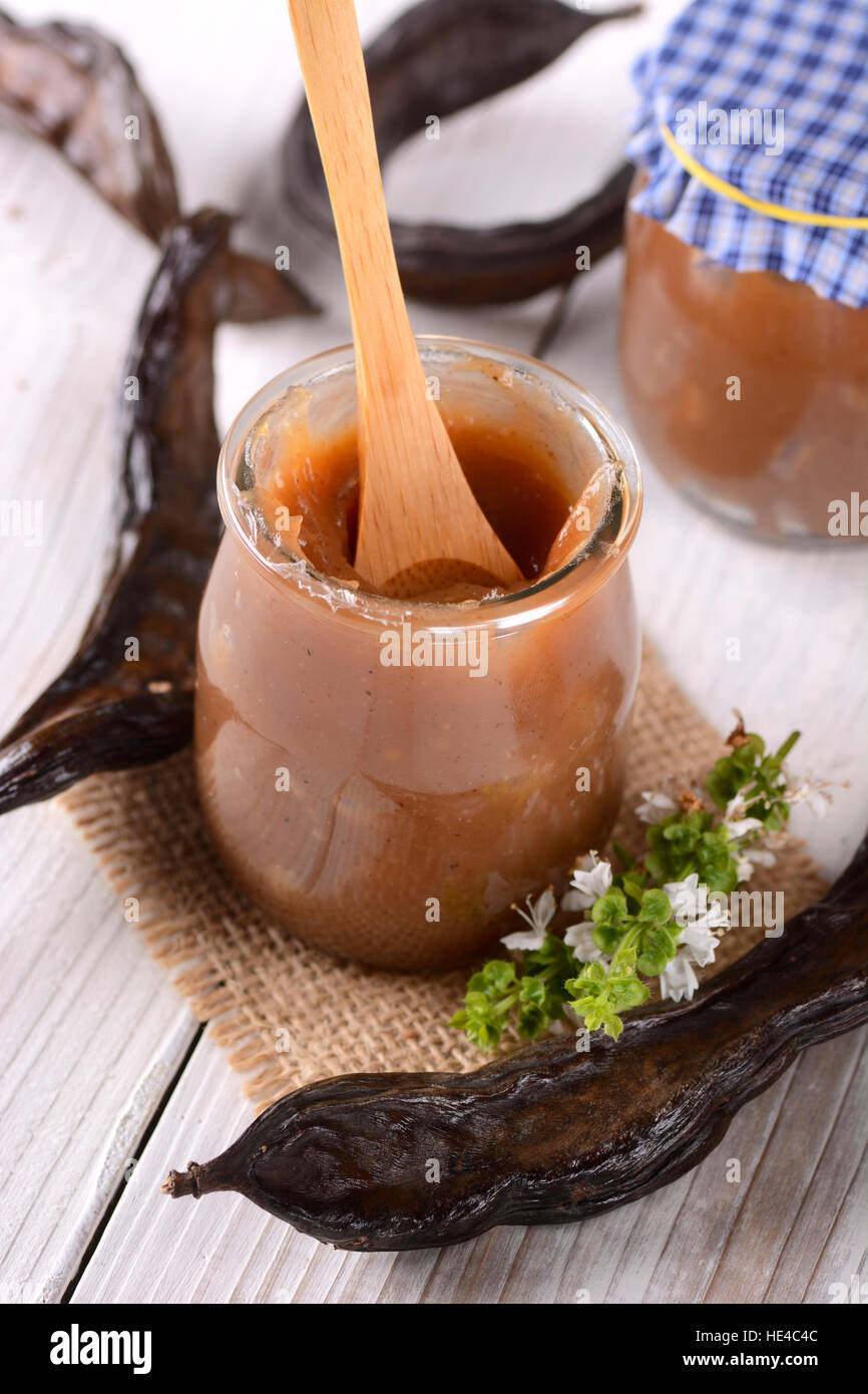 carob jam in glass jar with fruit around Stock Photo - Alamy