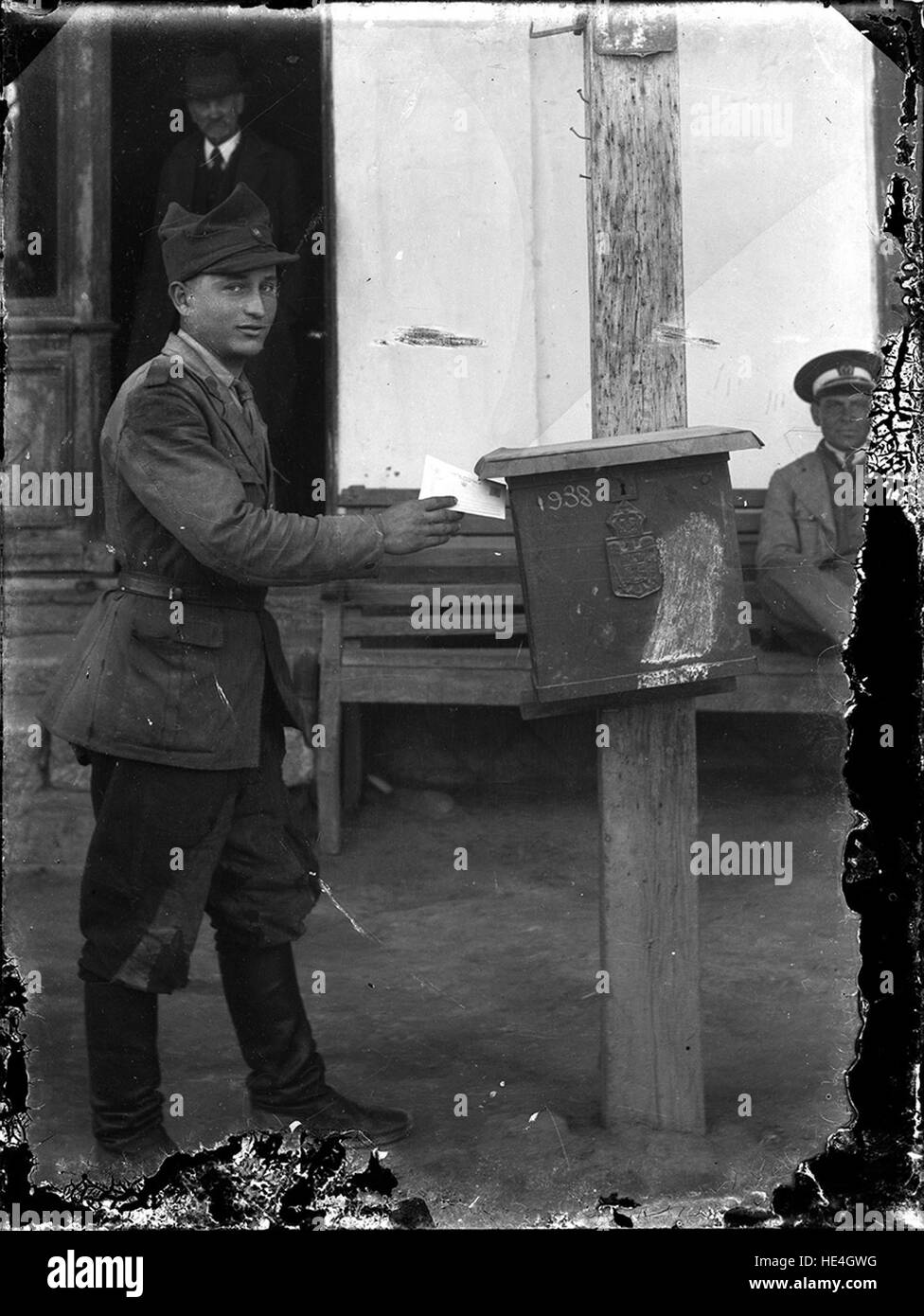 A soldier placing a letter in a mailbox during the early 20th century ...