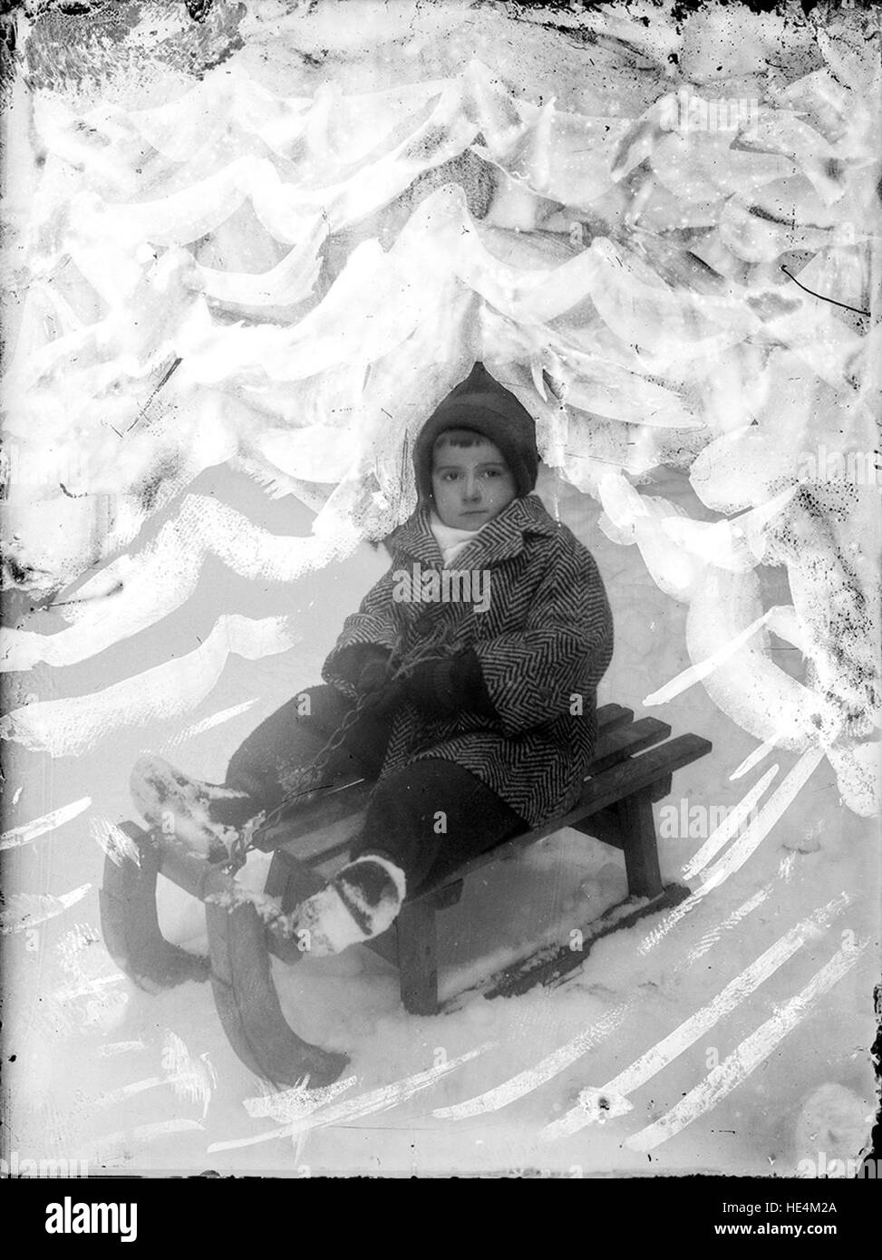 A child on a sled, wearing a crimson mask, captured in a moment from ...