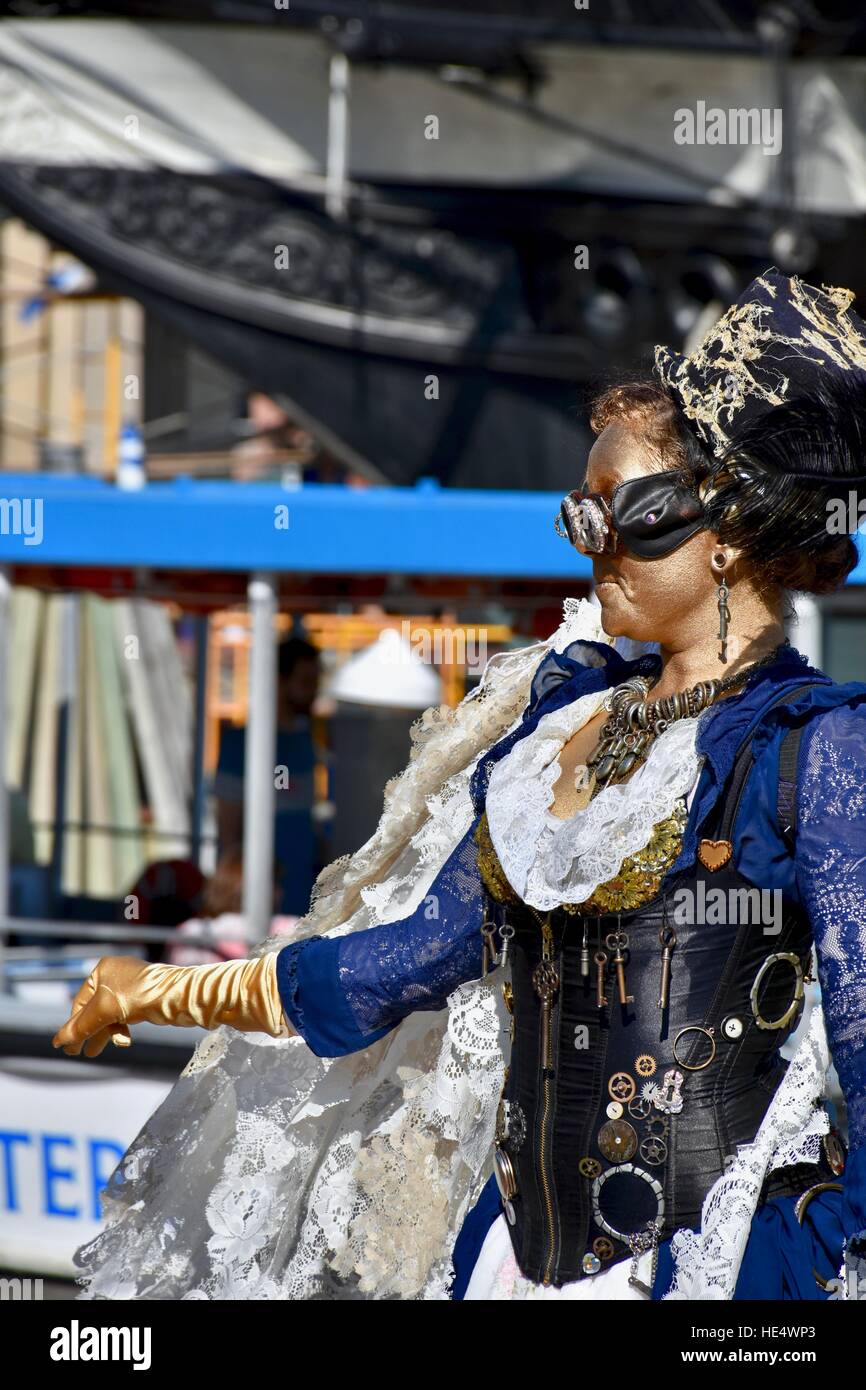 A woman in an old fashioned dress with her face painted gold dancing ...