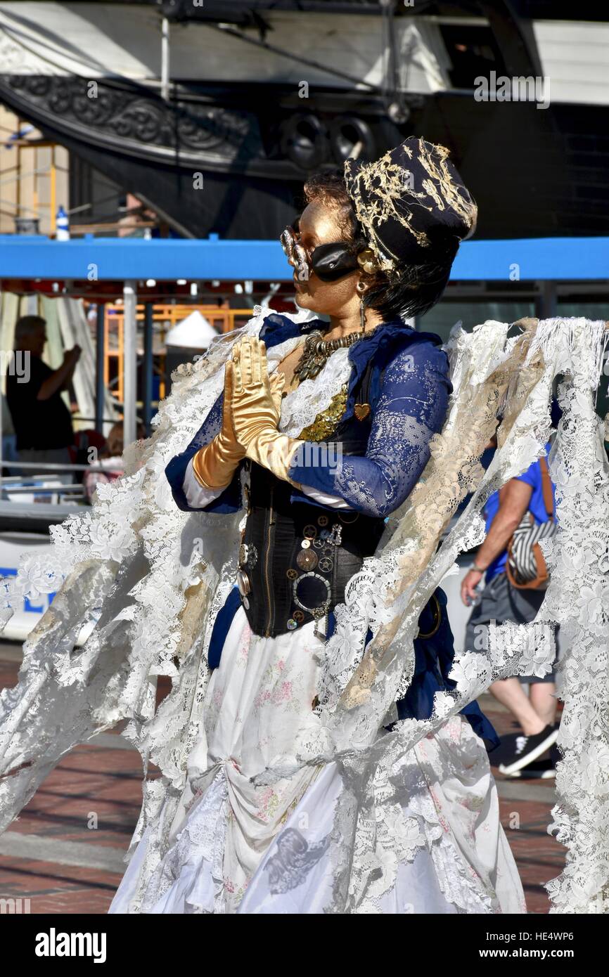 A woman in an old fashioned dress with her face painted gold dancing ...
