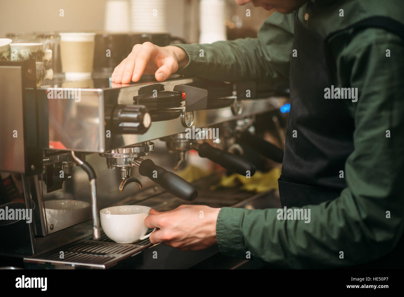 Male waiter standing against coffee machine Stock Photo - Alamy