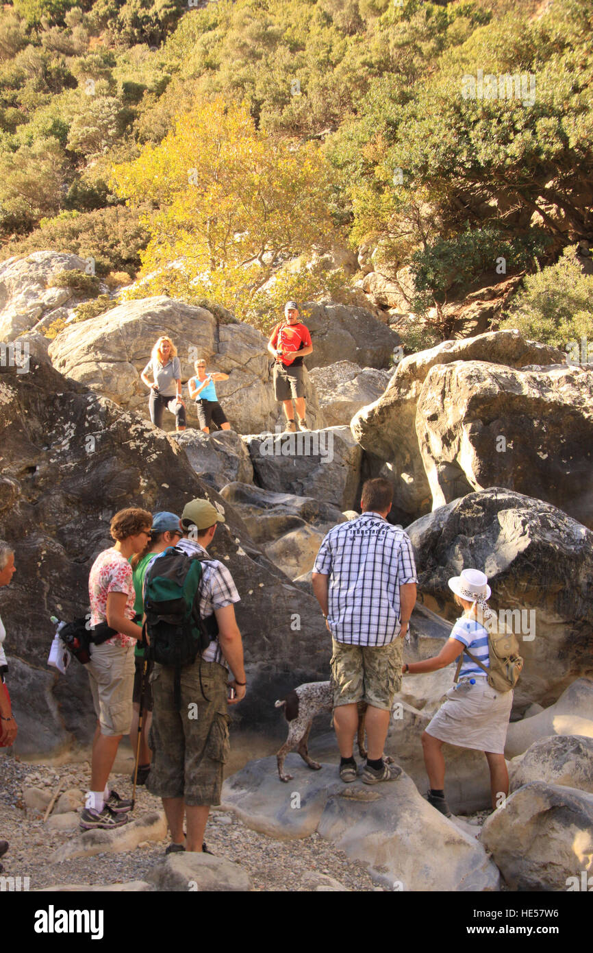 Tourists and holidaymakers on a guided walk along a dry river bed gorge ...