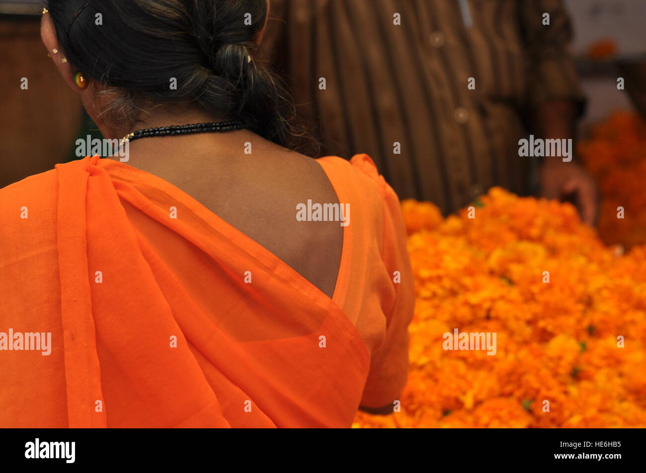 Indian woman in orange sari and orange flowers as background Stock ...