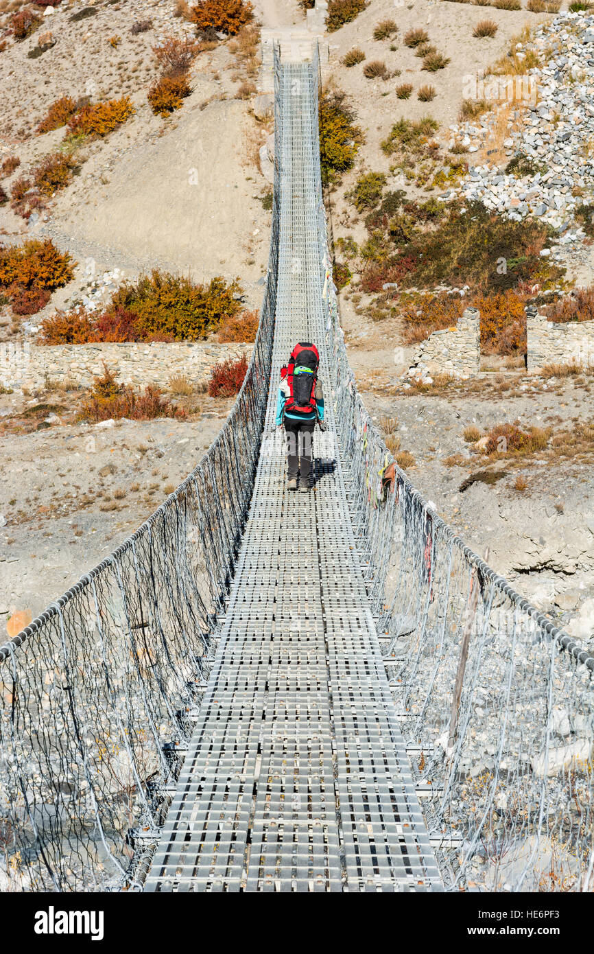Trekker crossing metal suspension bridge Stock Photo - Alamy