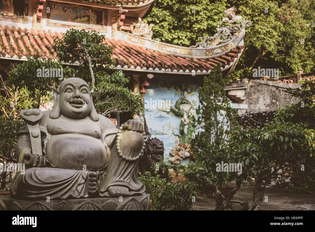 Jolly chubby Buddha statue in front of small Buddhist temple on Marble ...
