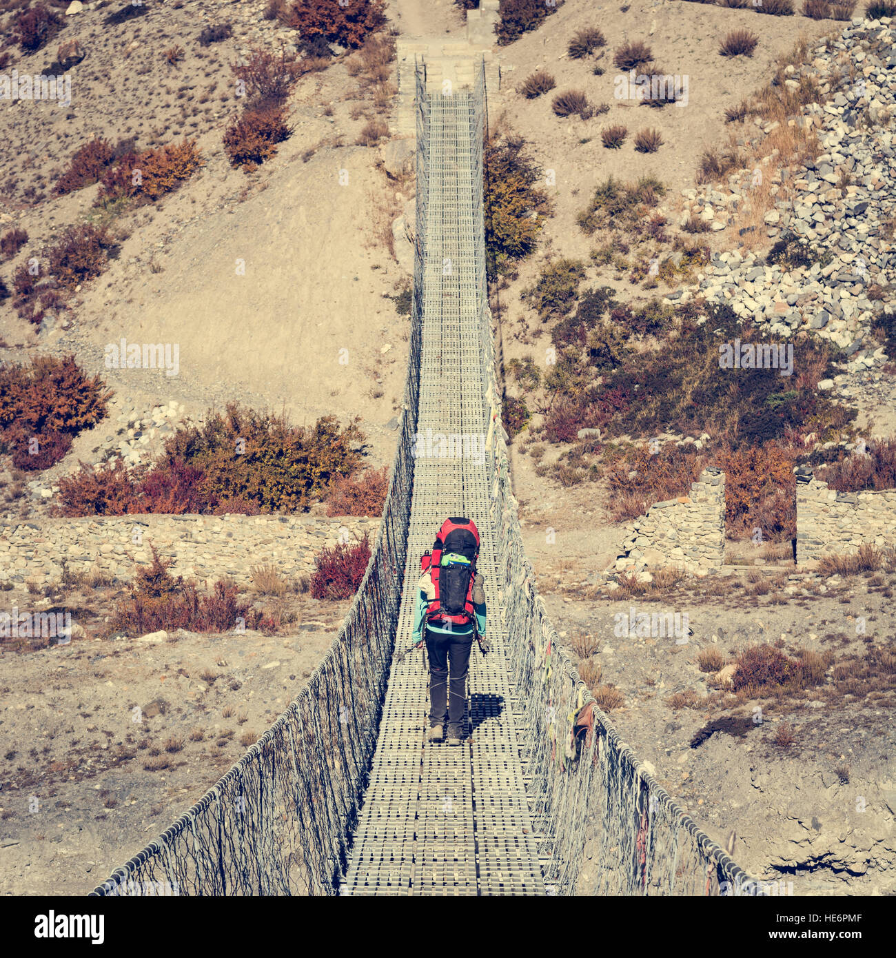 Trekker crossing metal suspension bridge Stock Photo - Alamy