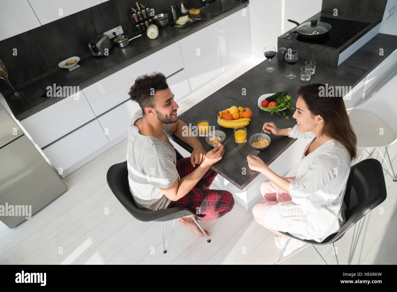Young Couple Having Breakfast In Kitchen, Asian Woman And Hispanic Man ...