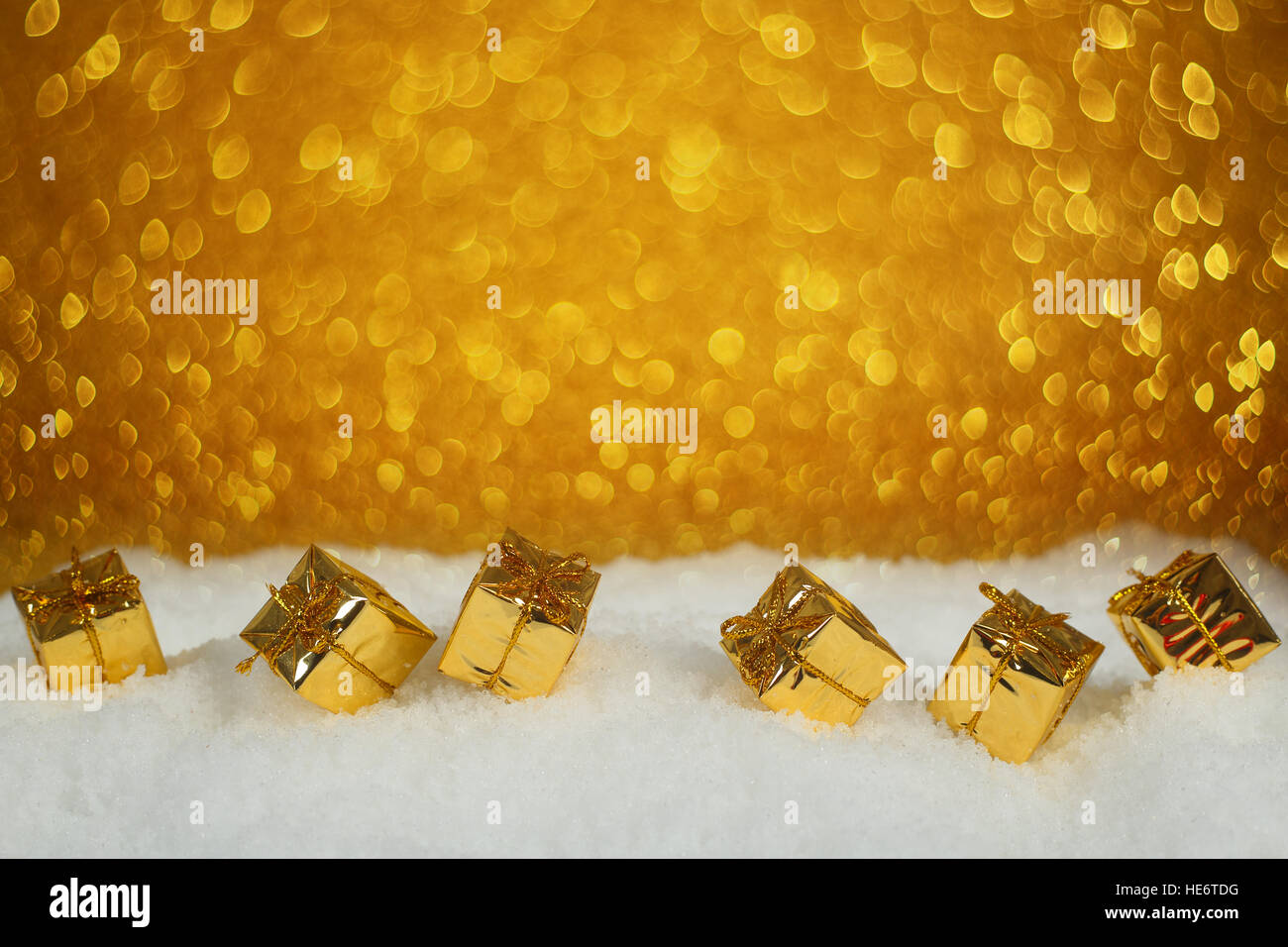 Golden christmas decorative gifts in the snow on glitter background ...