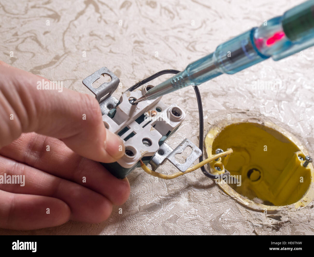 Hand holding a screwdriver pointing at a damaged electric socket Stock ...