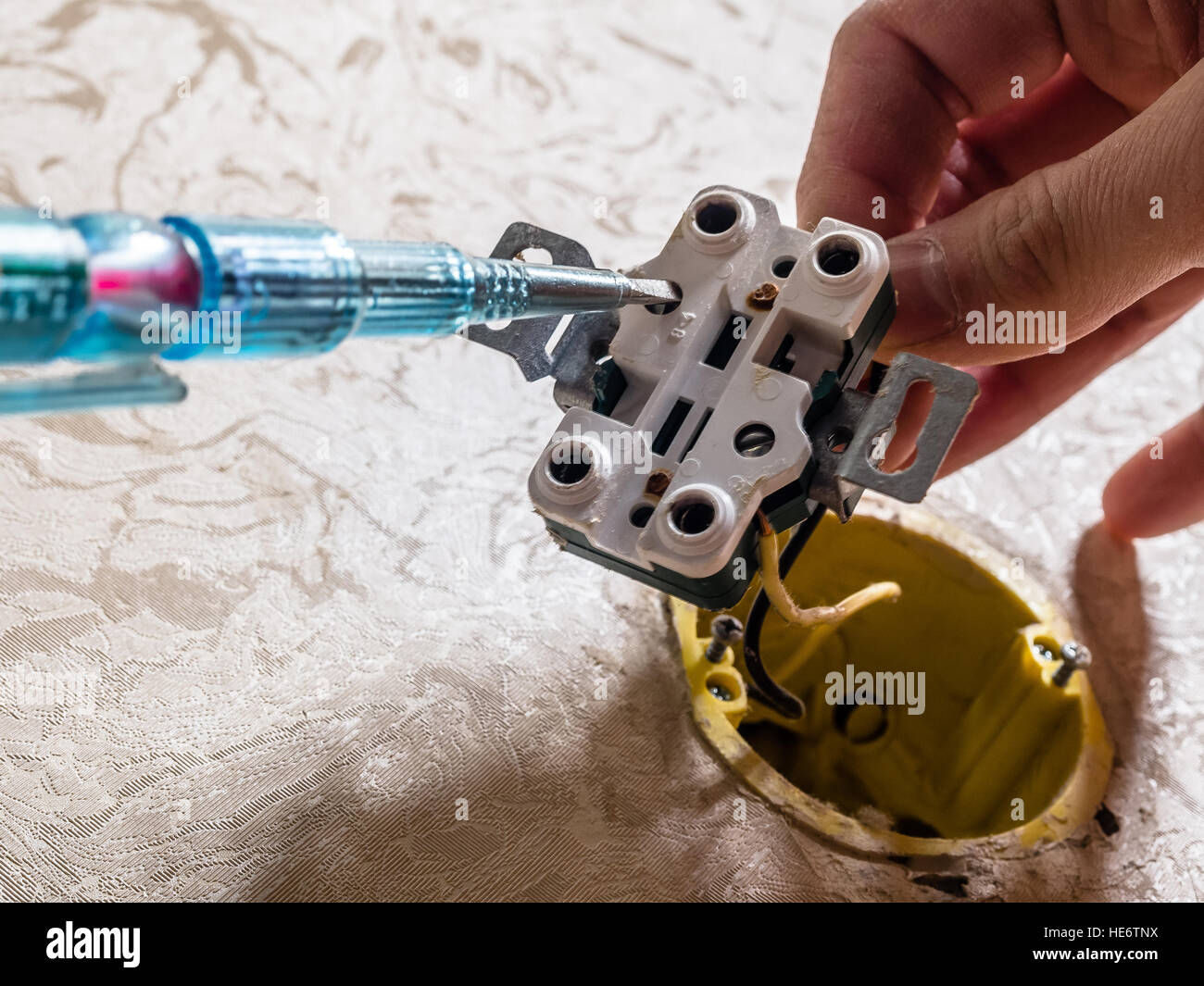 Hand holding a screwdriver pointing at a damaged electric socket Stock ...