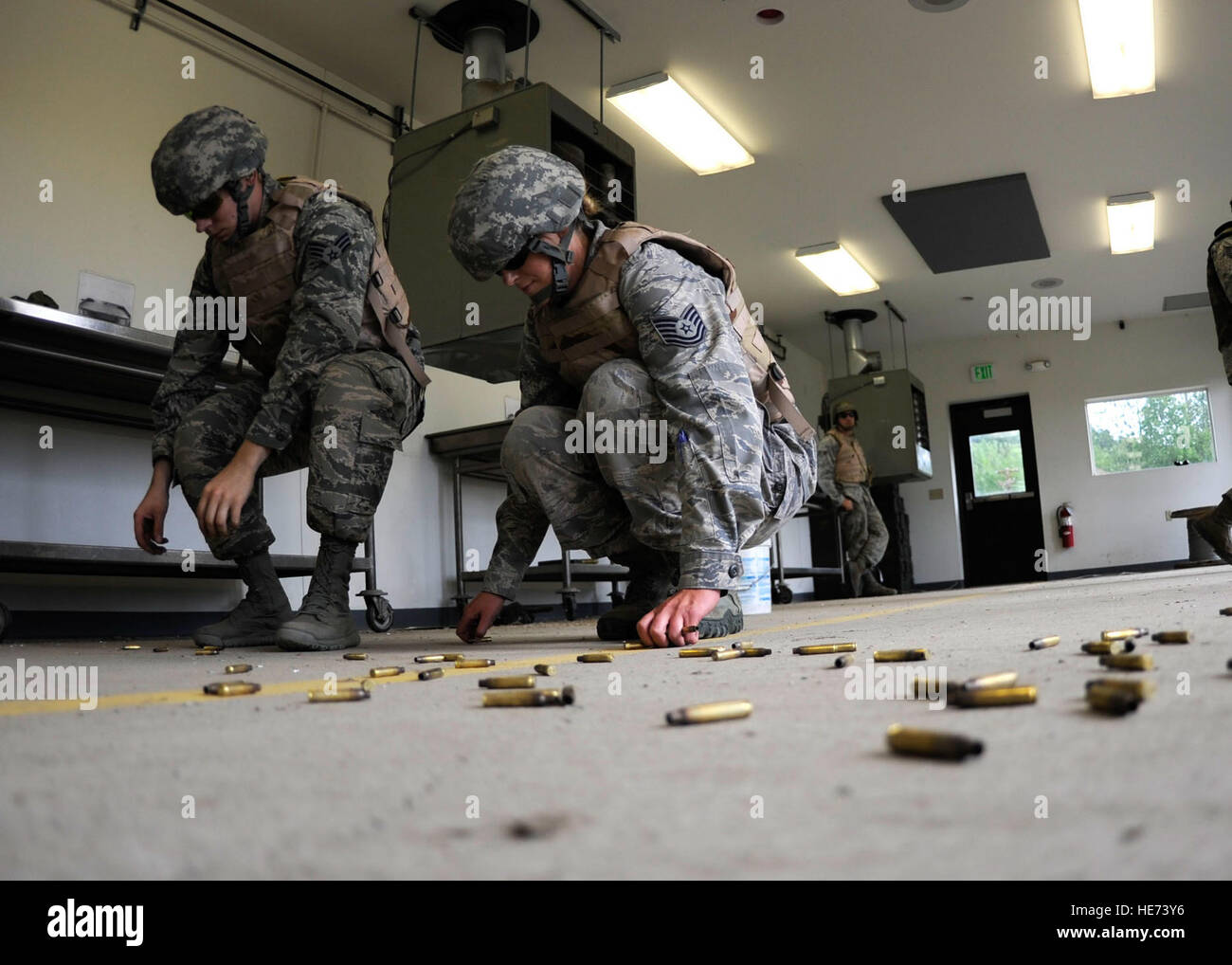 Airmen collect expended brass shell casings after firing an M-4 Carbine ...