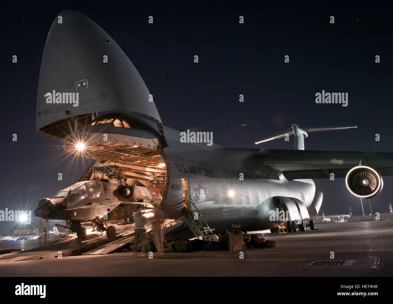 Airmen and soldiers load an AH-64 Apache attack helicopter onto a C-5B ...