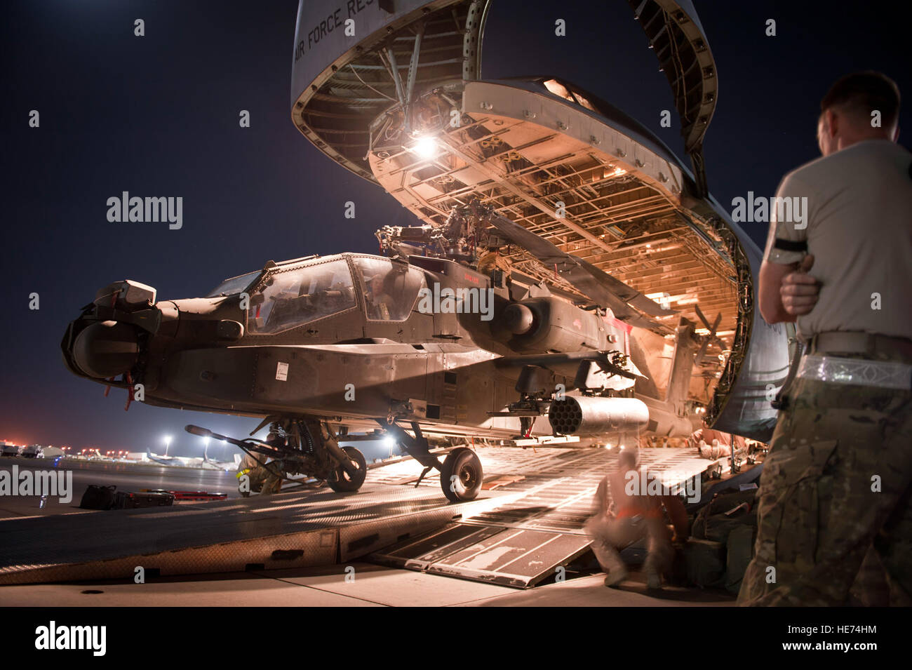 Airmen and soldiers load a U.S. Army AH-64 Apache attack helicopter ...