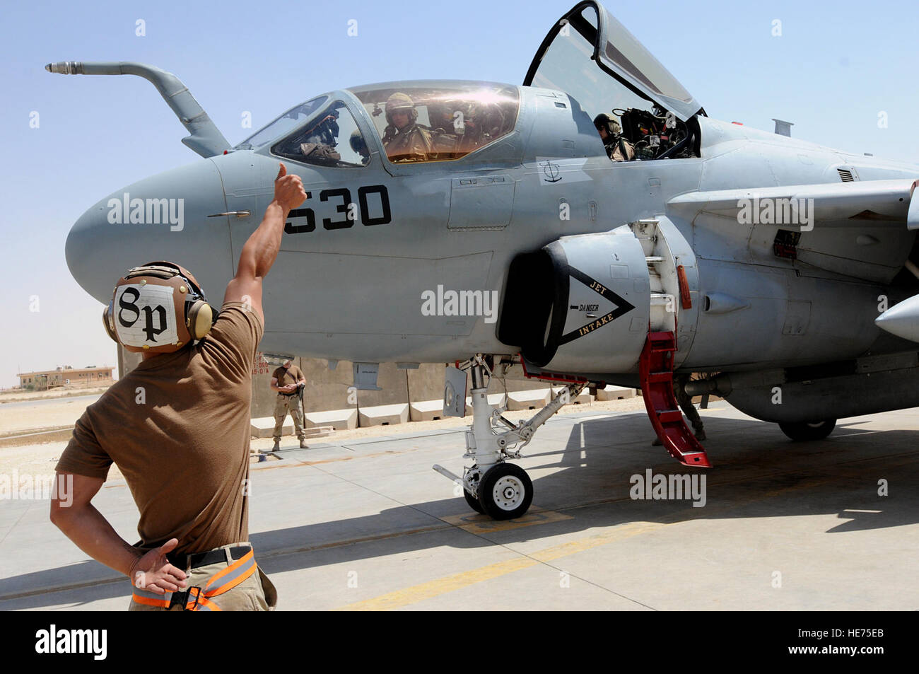 Navy maintenance personnel signal the pilot during pre-flight checks as ...