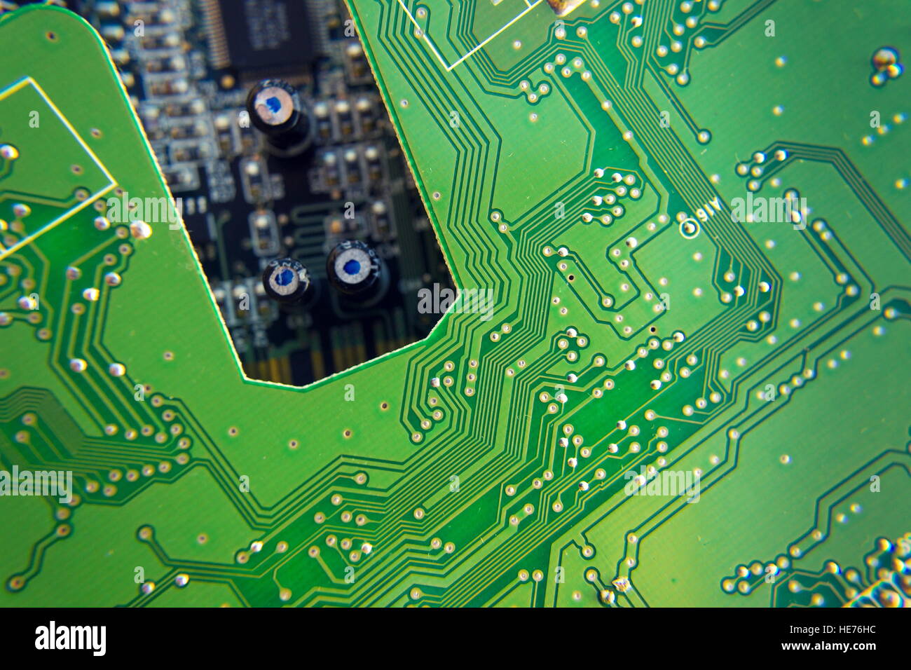 Filtered green computer motherboard circuit above blue motherboard hole ...