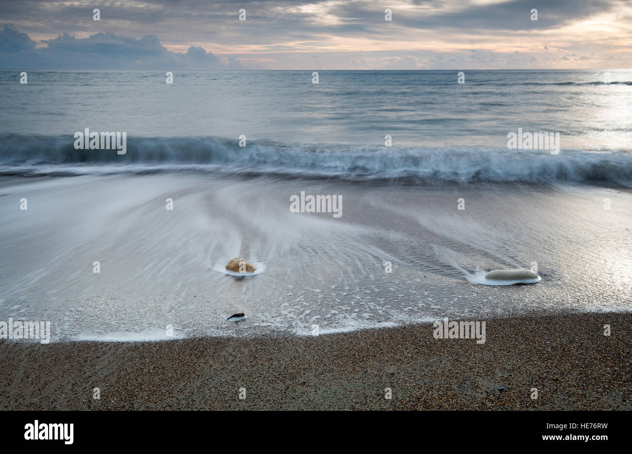 Pebbles on the beach and flowing sea water during sunset creating nice ...