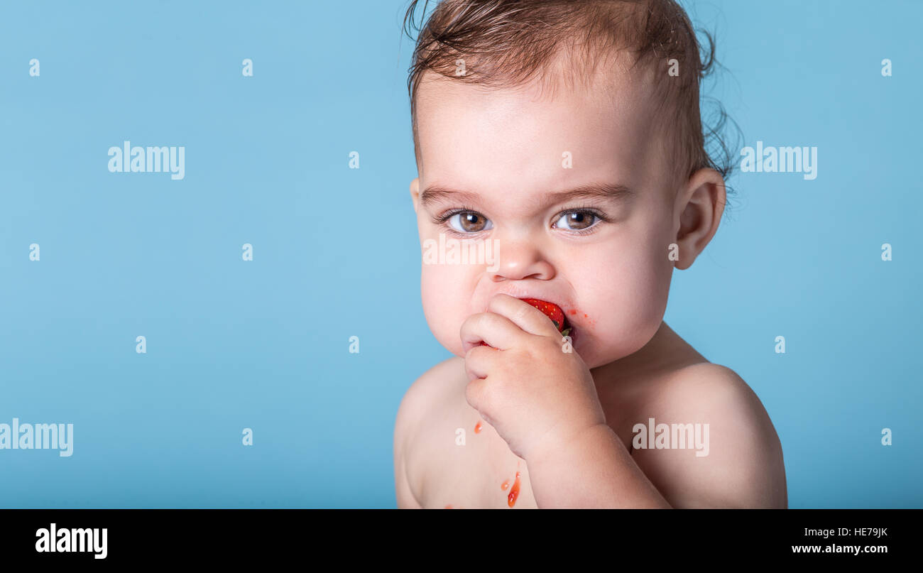Baby Munching Sour Strawberry and Pulling Squint Face Stock Photo - Alamy
