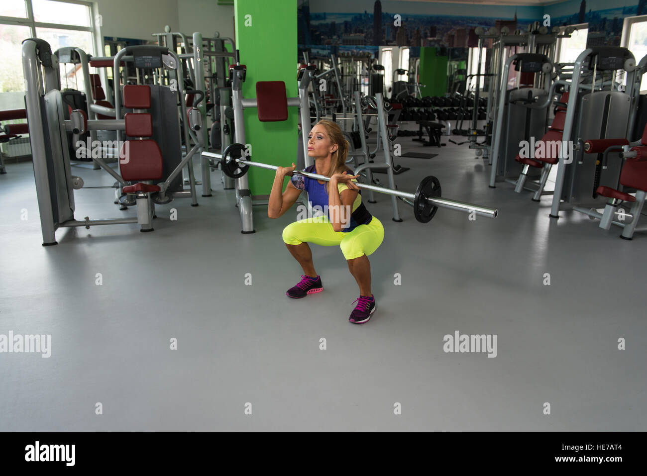 Mature Woman Working Out Legs With Barbell In A Gym - Squat Exercise ...