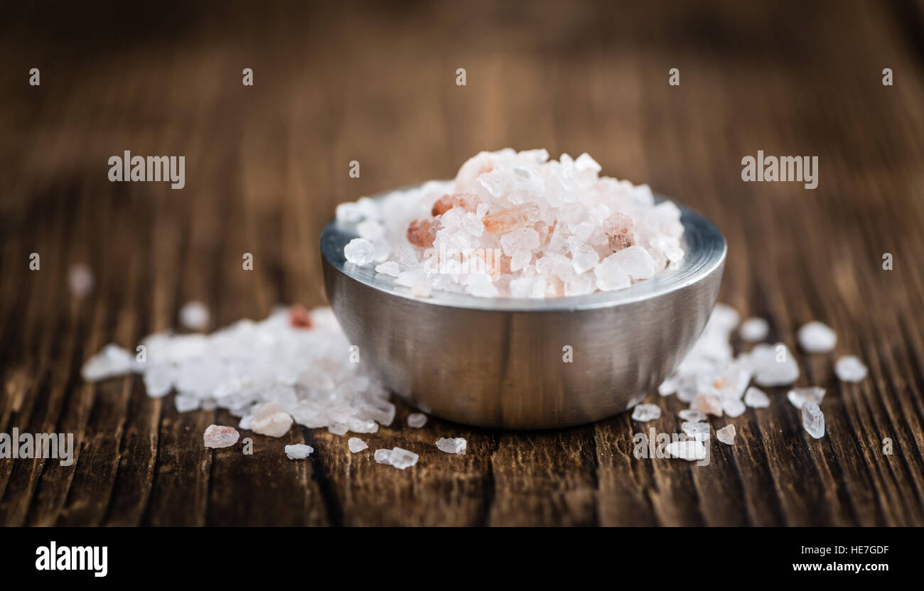 Salt (pink) on an old wooden table as detailed close-up shot (selective ...