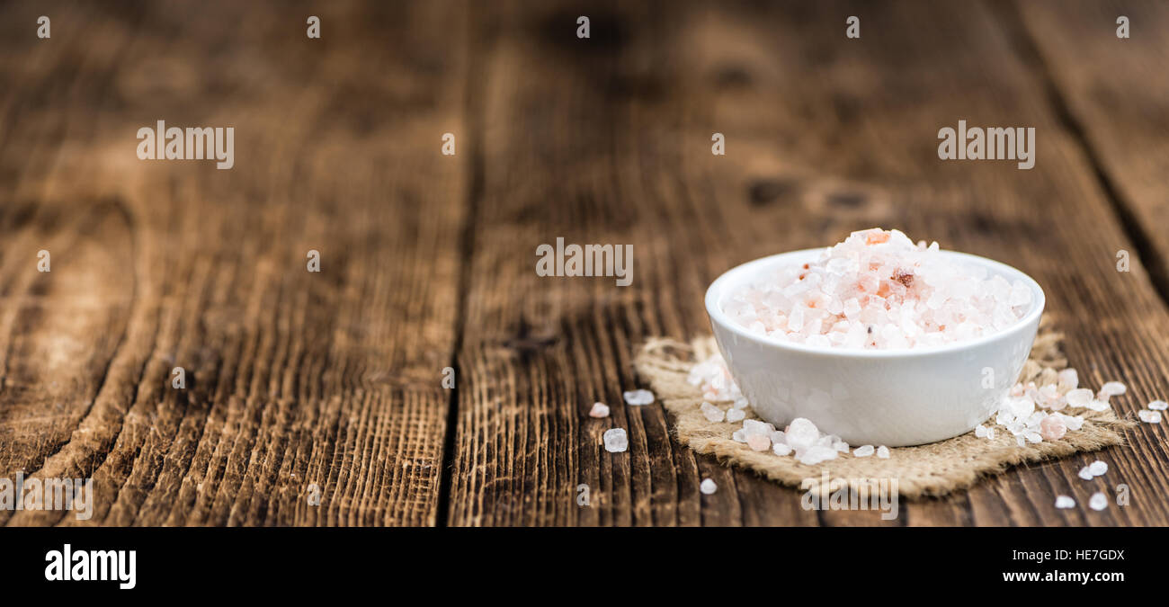 Salt (pink) on an old wooden table as detailed close-up shot (selective ...
