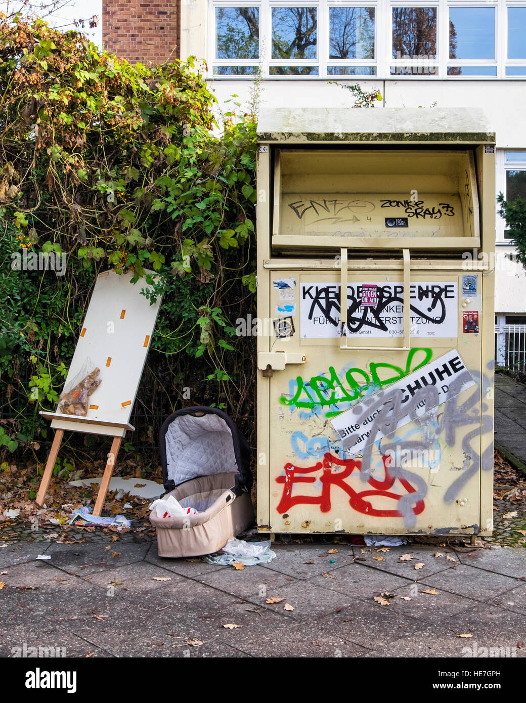 Clothes recycling bin with discarded easel and baby carrycot Stock ...