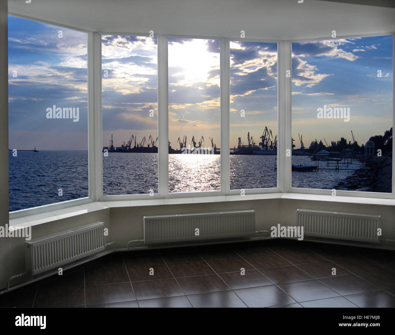 window with view of evening sea port docks and cranes in Berdyansk ...