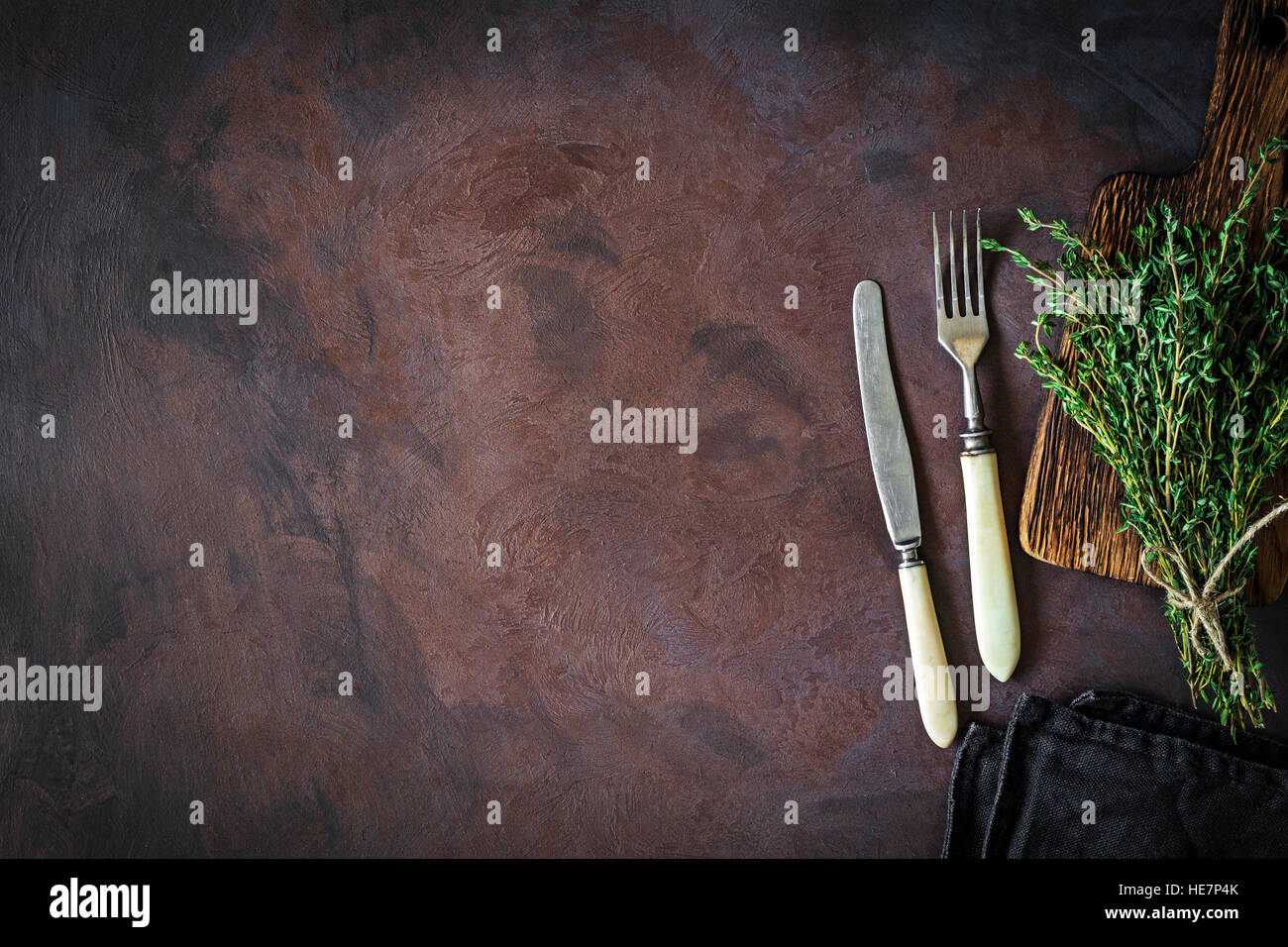 Vintage silverware with ivory handle, dark textile, wooden cutting ...