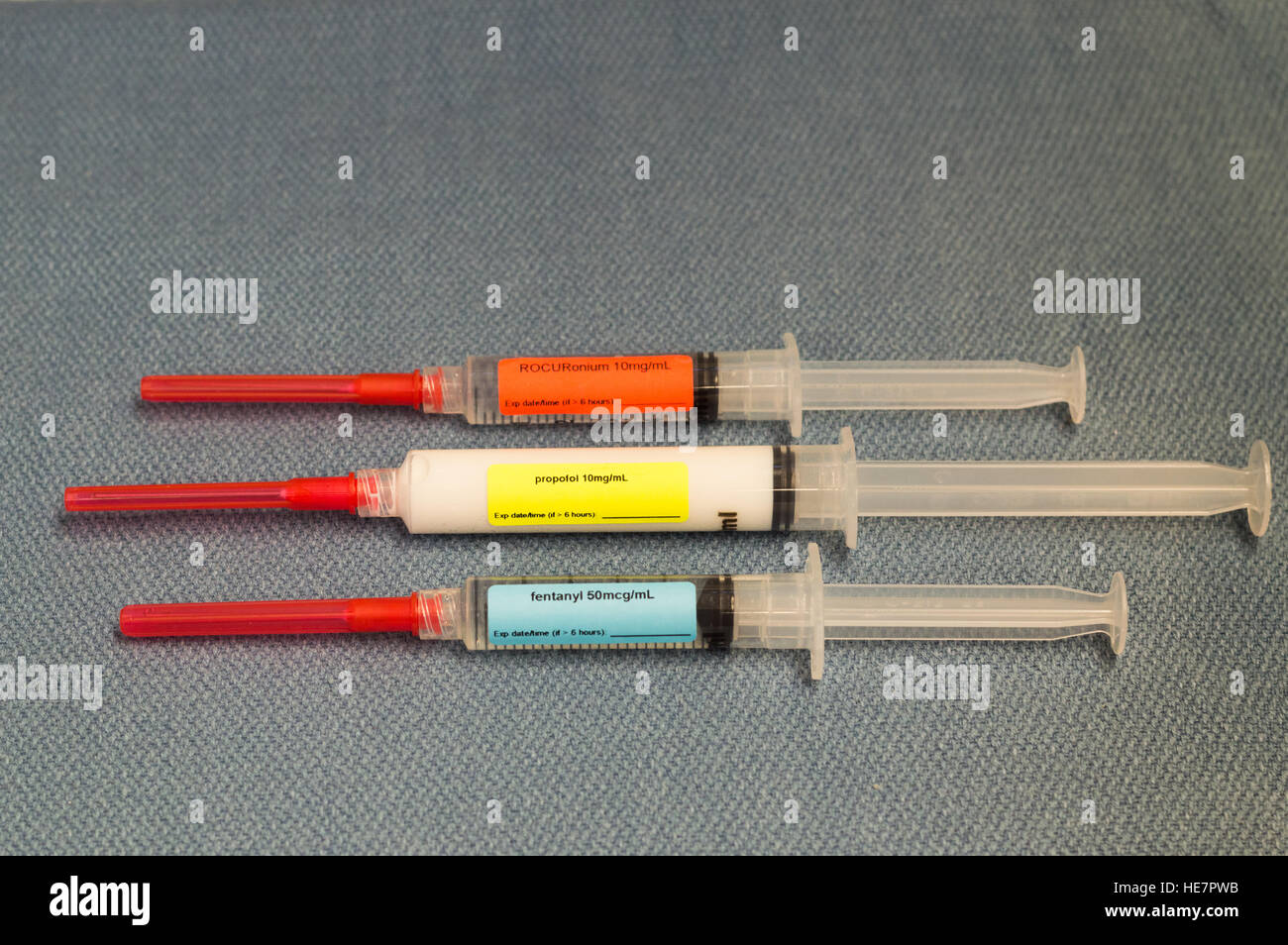 Three syringes with red capped needles containing labeled generic ...